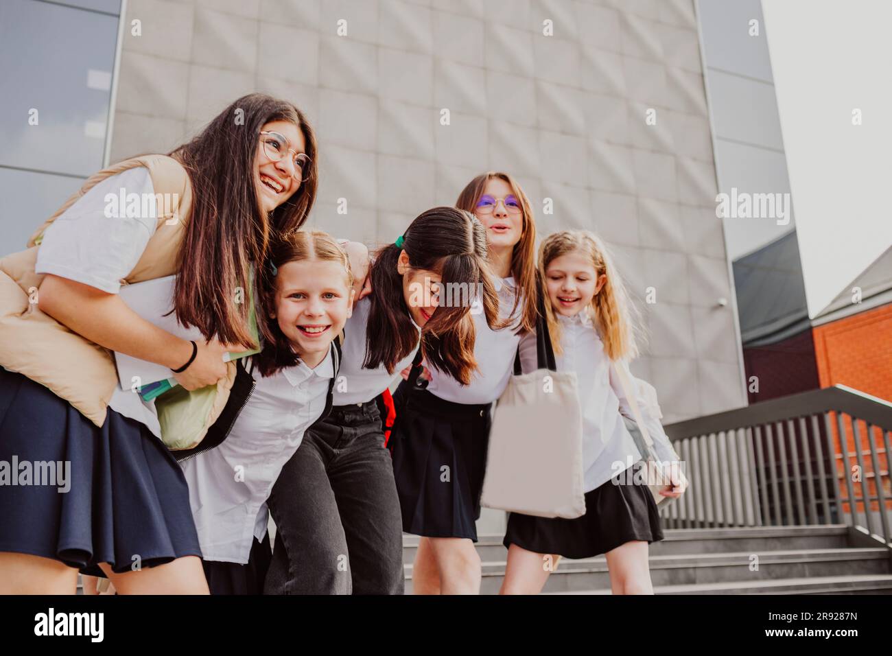 Friends having fun standing in front of school building Stock Photo - Alamy