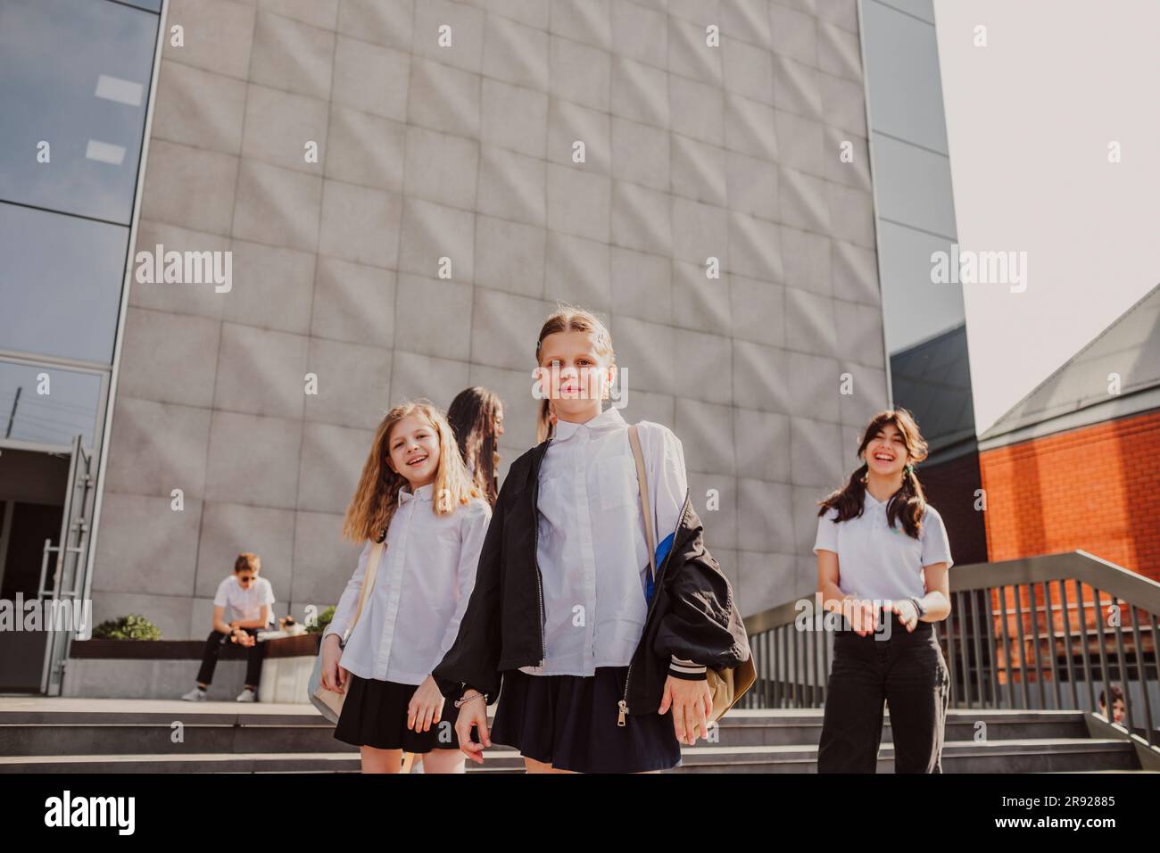 Schoolgirls spending leisure time standing in front of school building ...
