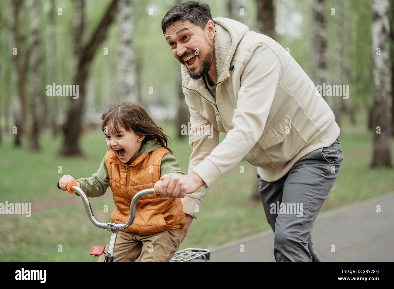Happy father helping son ride bicycle at park Stock Photo - Alamy