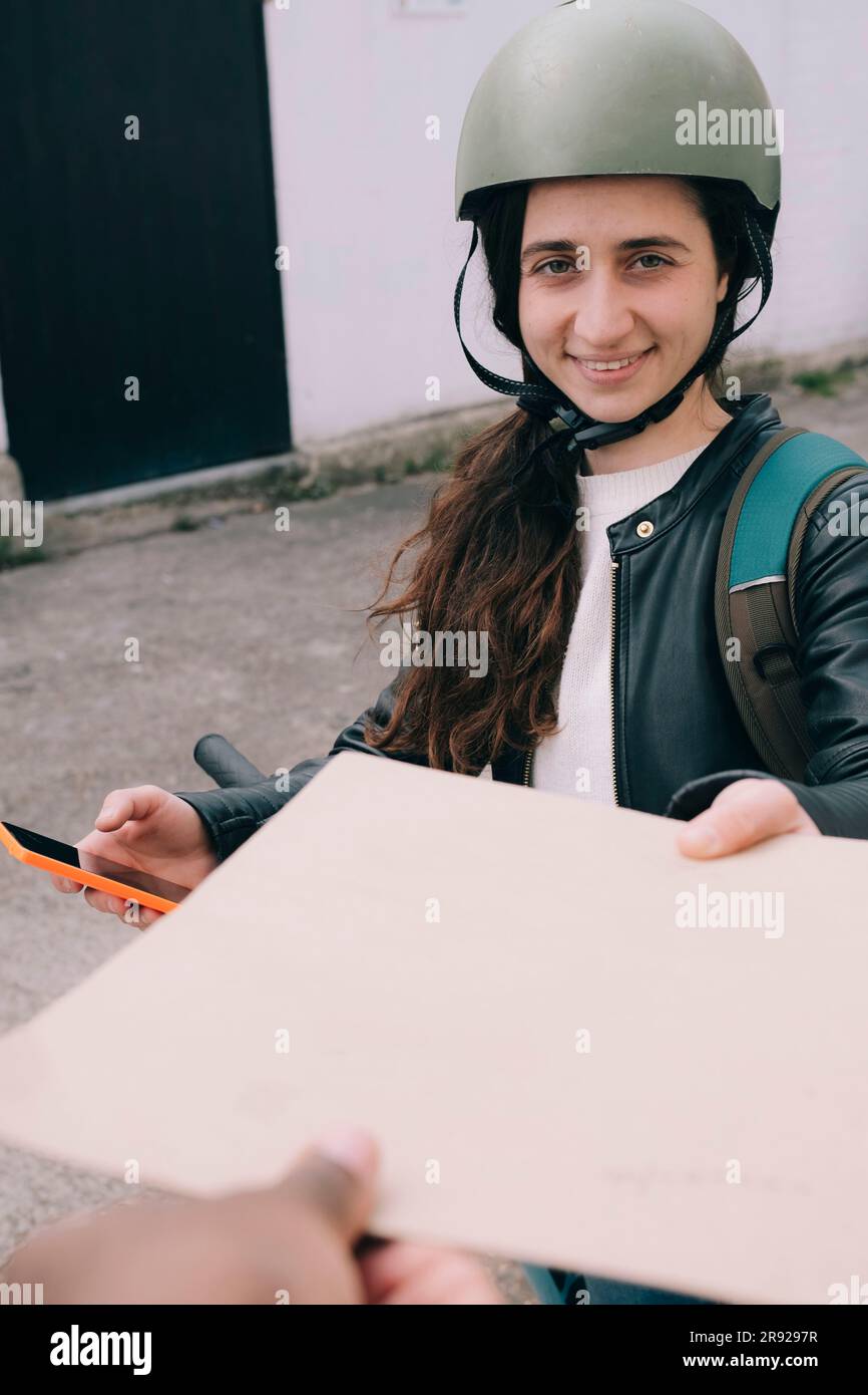 Happy delivery person giving envelope to customer Stock Photo - Alamy