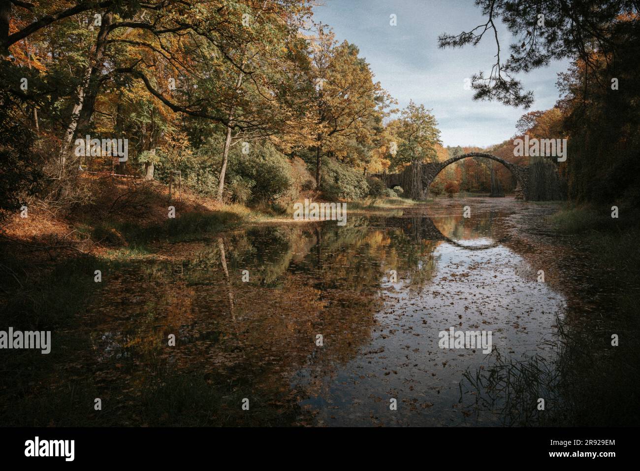 Germany, Saxony, Lake in autumn with Rakotzbrucke bridge in background ...