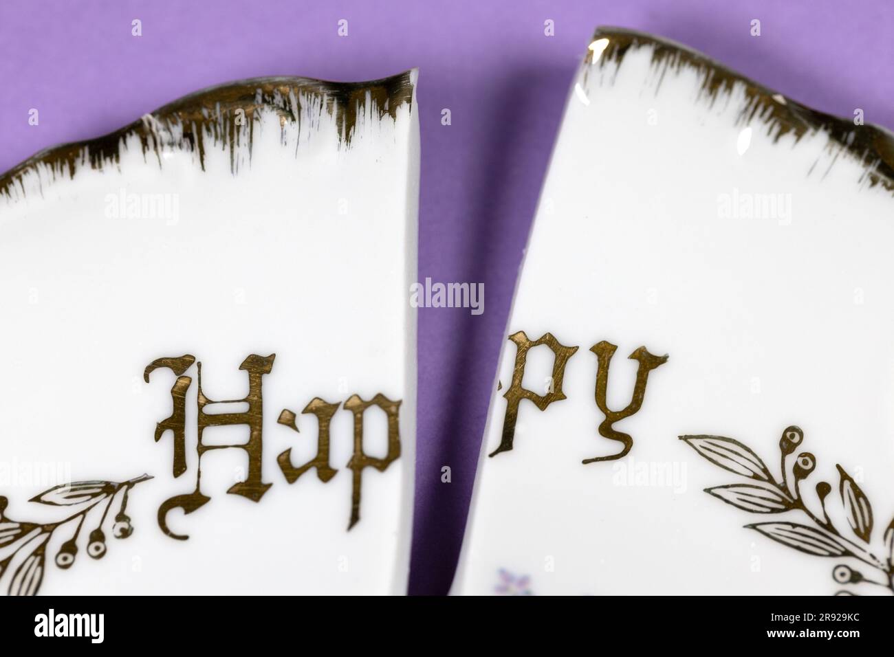 A broken plate, splitting the written word "happy Stock Photo - Alamy