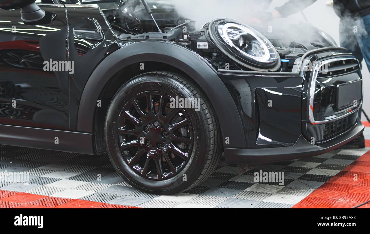 Side view of detailing process of steam cleaning black car engine from ...