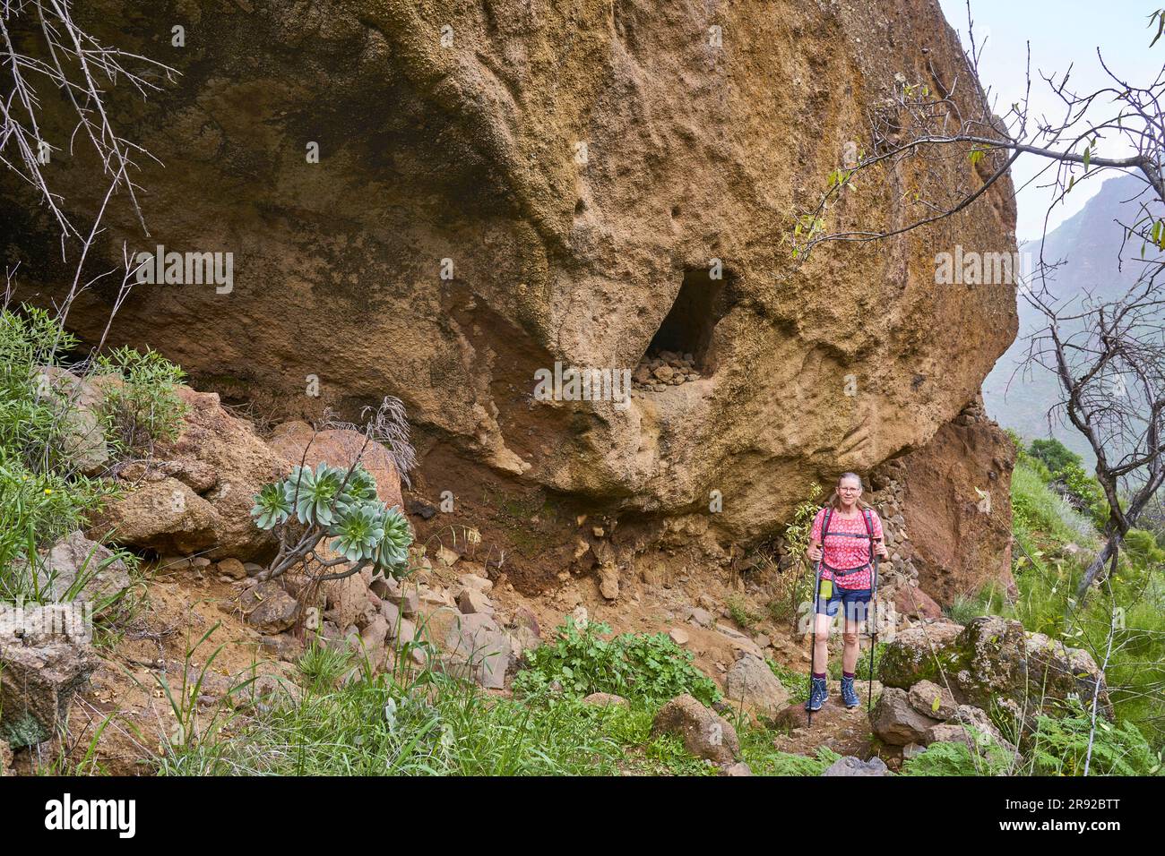 Hiker in front of rocks with living and storage caves in the Barranco ...