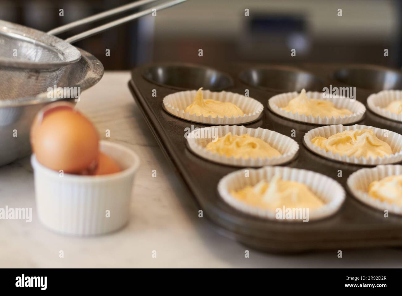 Cupcake tray, batter and baking in a kitchen with muffin mix or wrapper ...