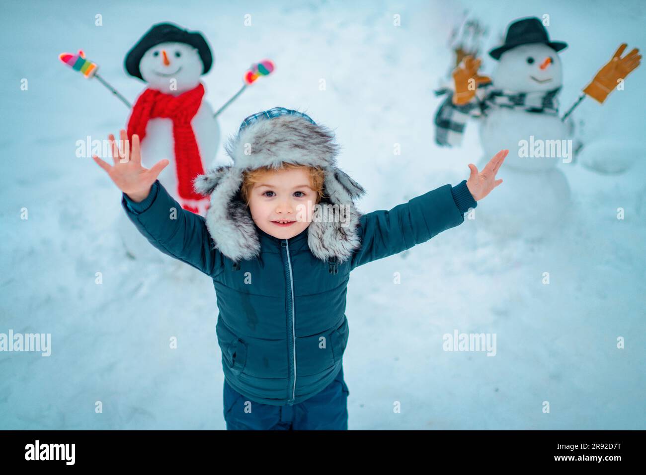 Beauty Winter child with snowman in frosty winter Park. Outdoor ...