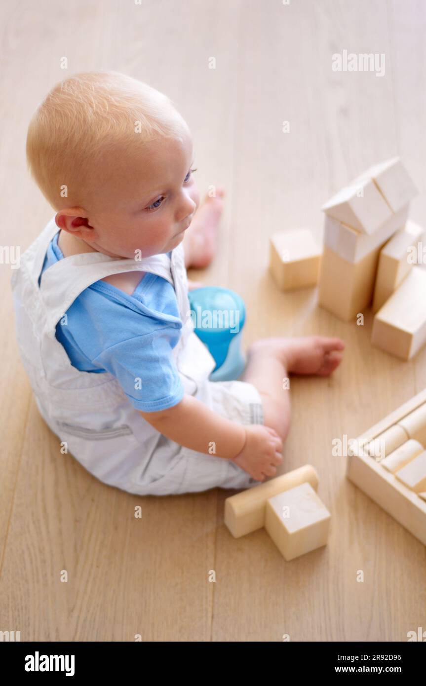 Little baby boy, toys and wooden blocks on floor for playtime, learning ...