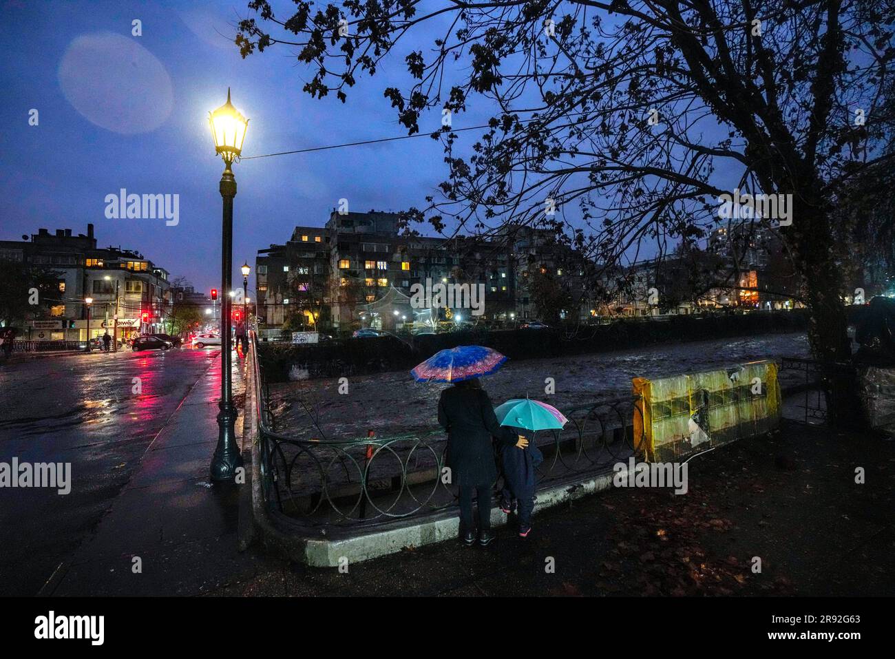 People watch the water level of the Mapocho River rise during a heavy ...