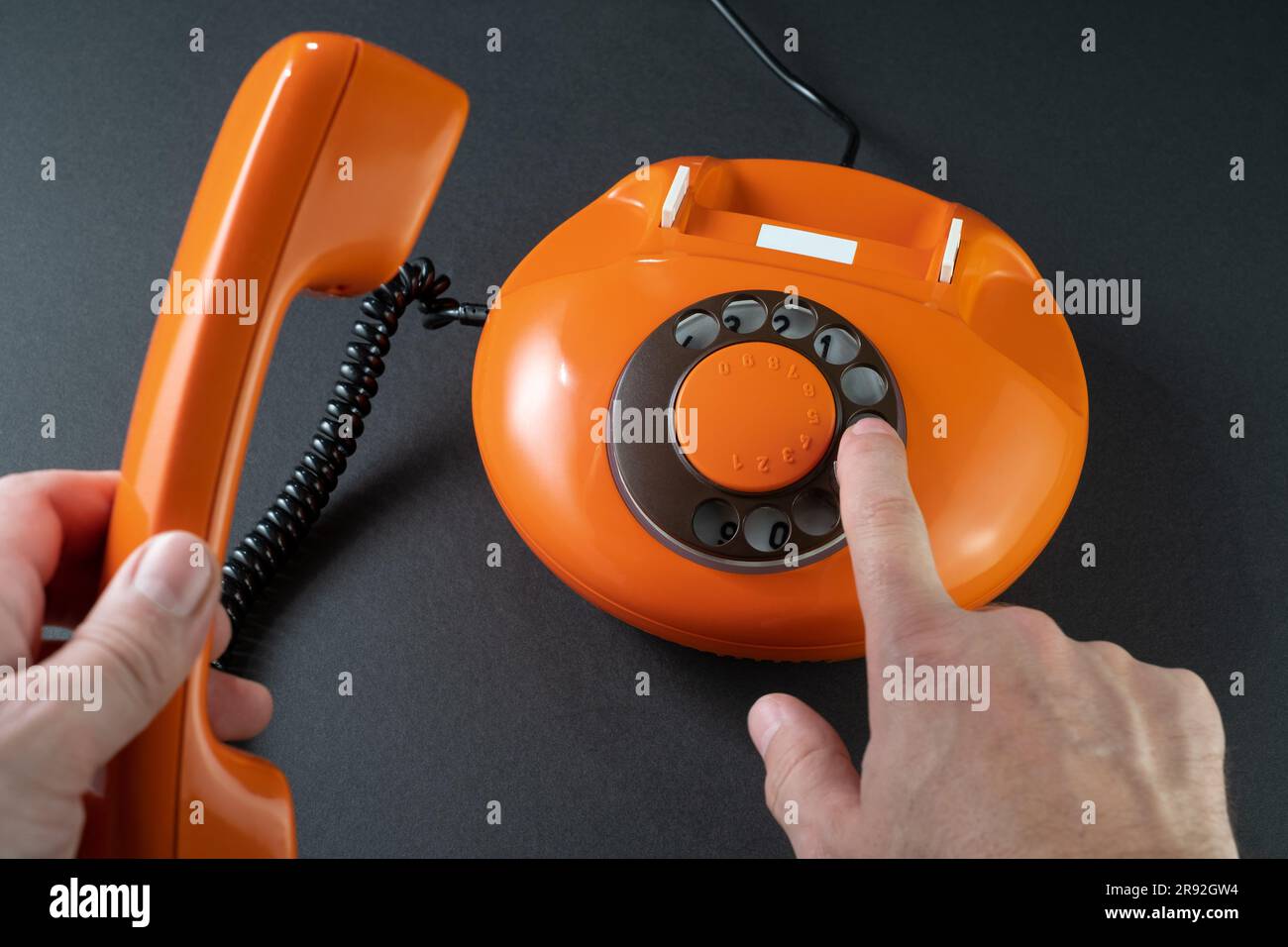Dialing Using rotary Disk on A vintage Orange color Rotary Phone. Land ...
