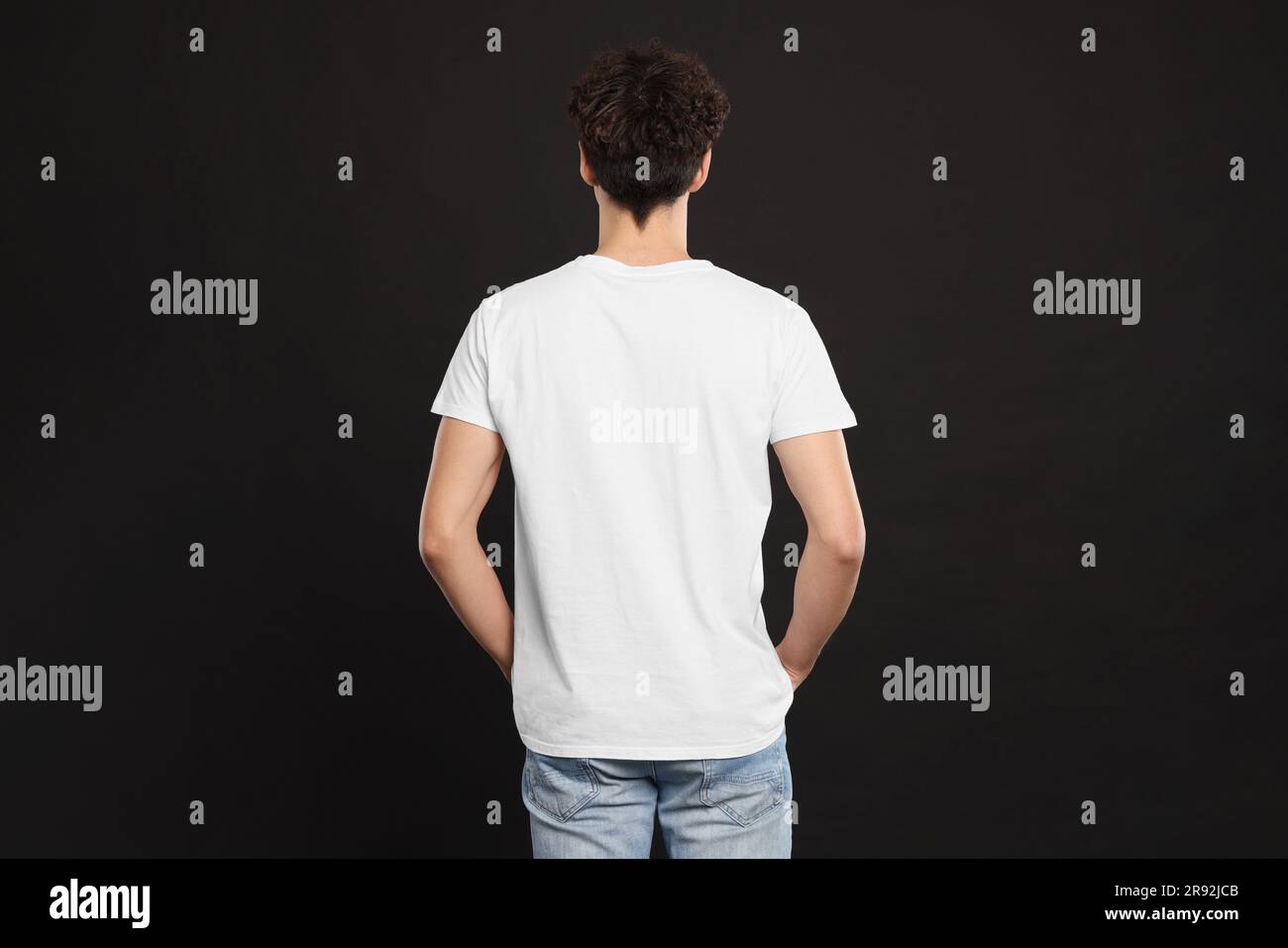 Man wearing white t-shirt on black background, back view. Mockup for ...