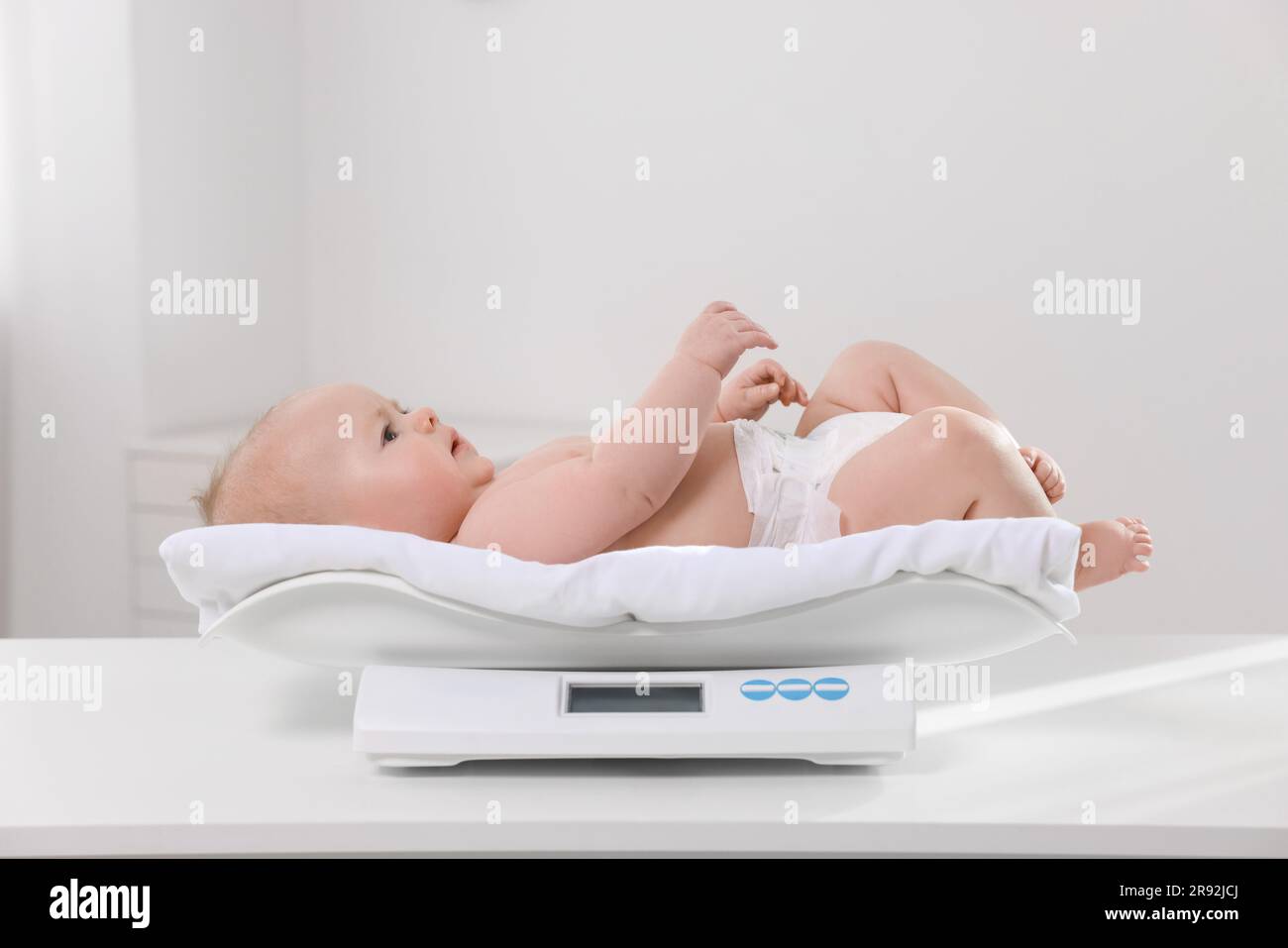 Cute little baby lying on scales in clinic Stock Photo - Alamy