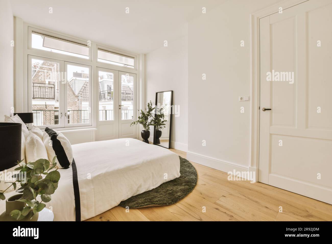a bedroom with white walls and wood flooring the room is well lit by ...