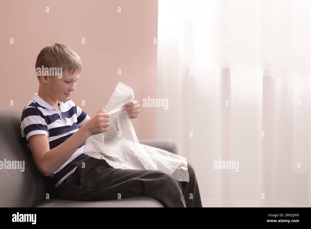 Boy popping bubble wrap at home, space for text. . Stress relief Stock ...