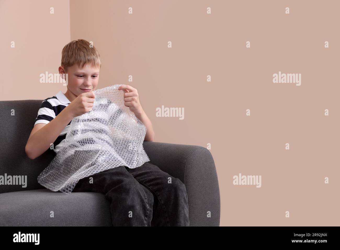 Boy popping bubble wrap at home, space for text. . Stress relief Stock ...