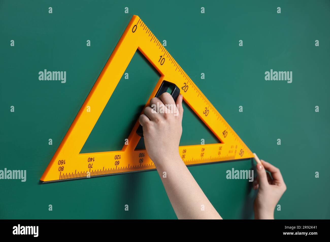 Woman drawing with chalk and triangle ruler on green board, closeup ...