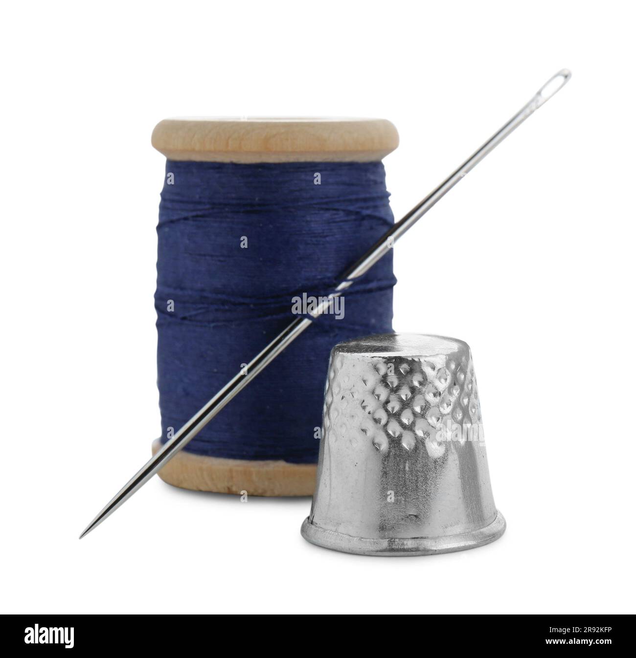 Thimble and spool of blue sewing thread with needle isolated on white ...