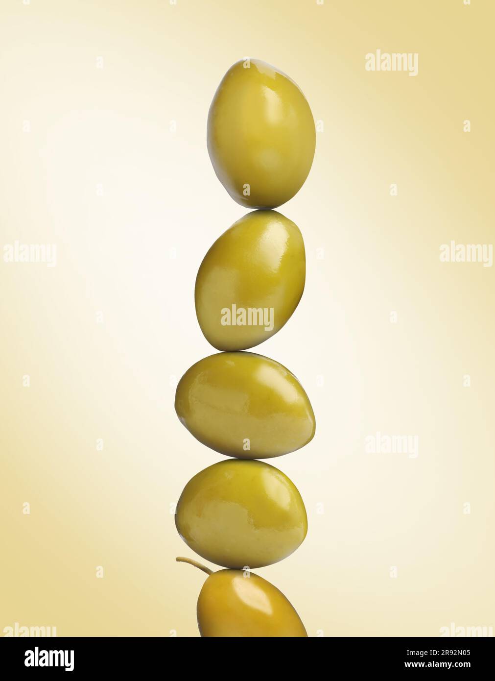 Stack of whole olives on pastel gold background Stock Photo - Alamy