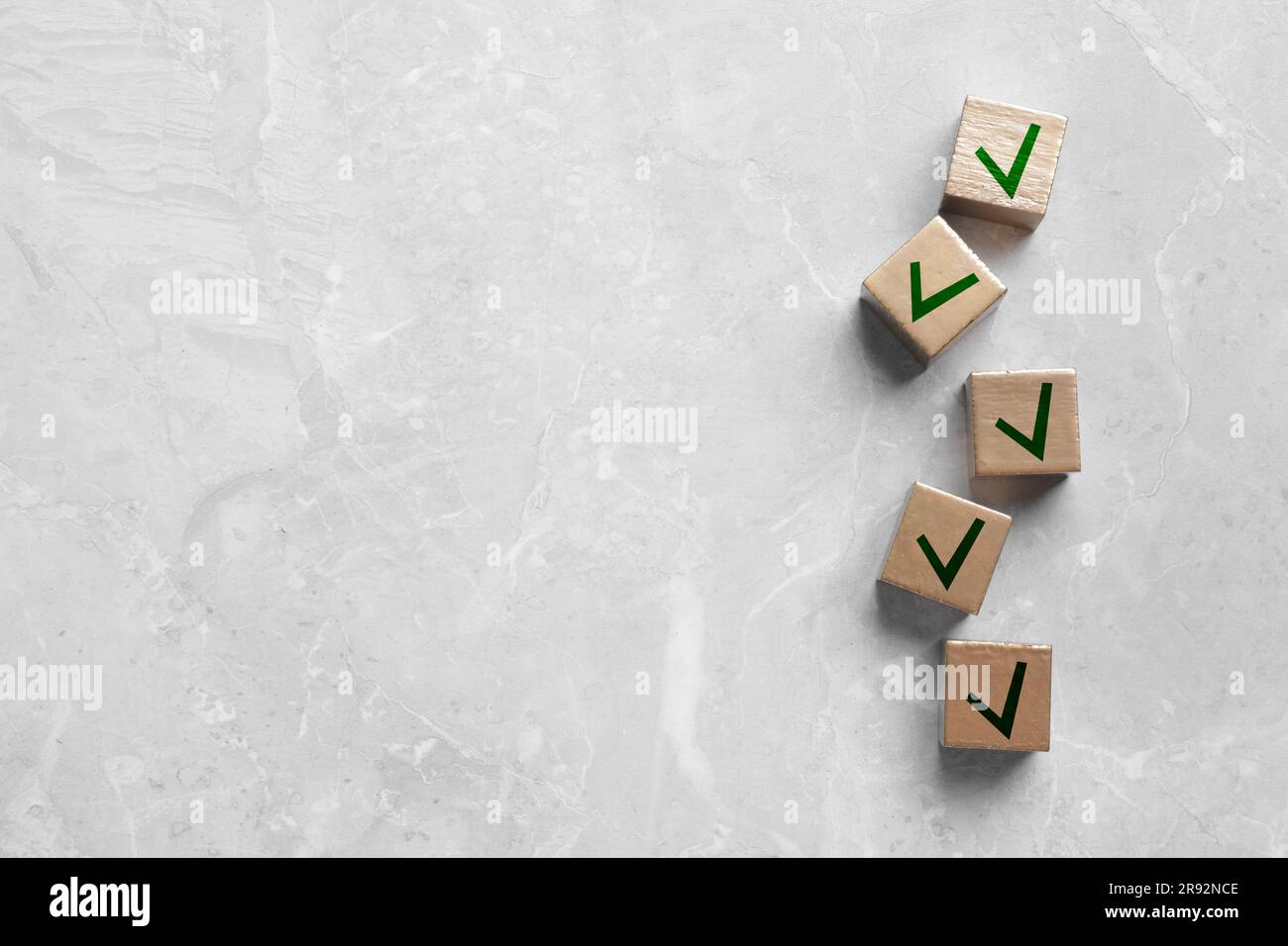 Cubes with check marks on light grey table, flat lay. Space for text ...