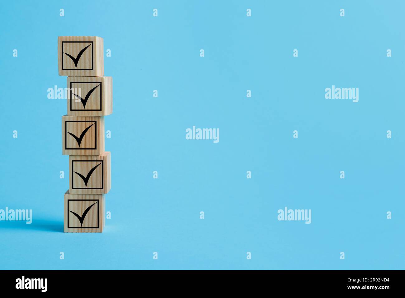 Stacked wooden cubes with check marks on light blue background. Space ...