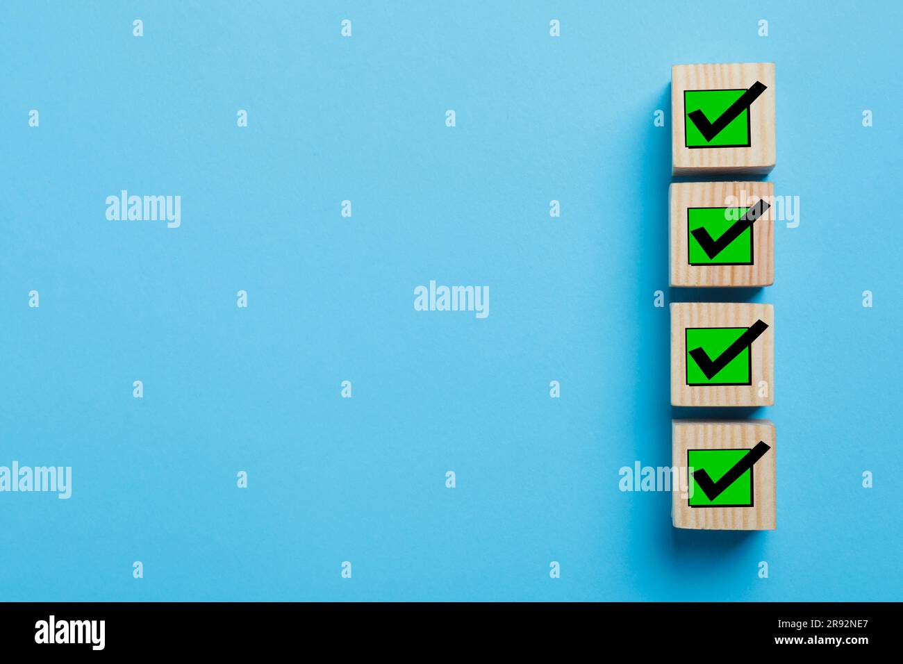 Wooden cubes with check marks on light blue background, top view. Space ...