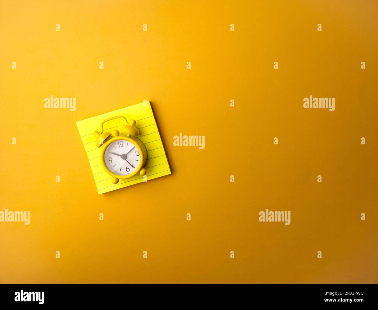 Top view yellow sticky note with alarm clock on a yellow background ...