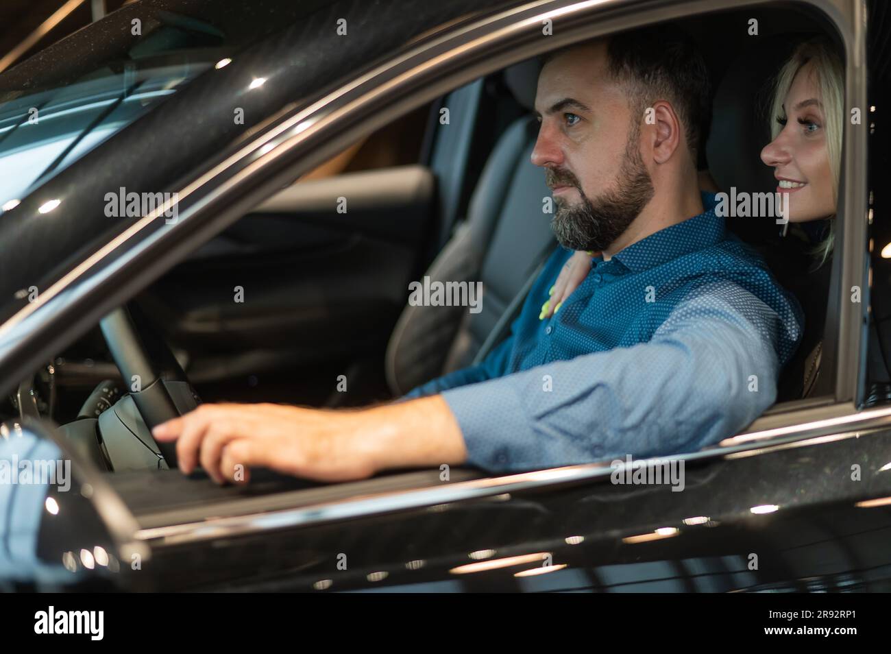 Happy married couple testing new car in car showroom Stock Photo - Alamy