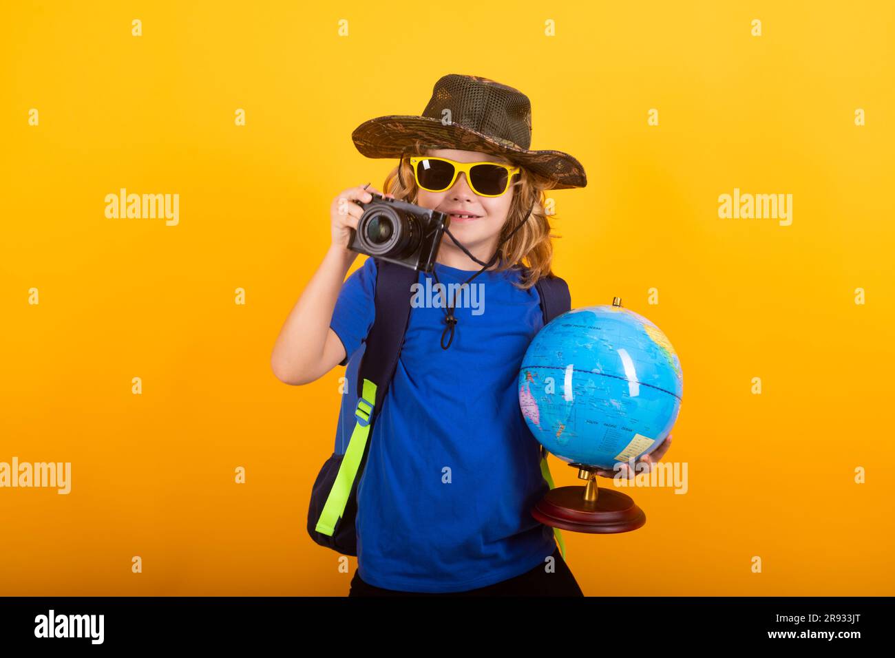Scout boy wearing explorer hat and backpack in studio yellow background ...