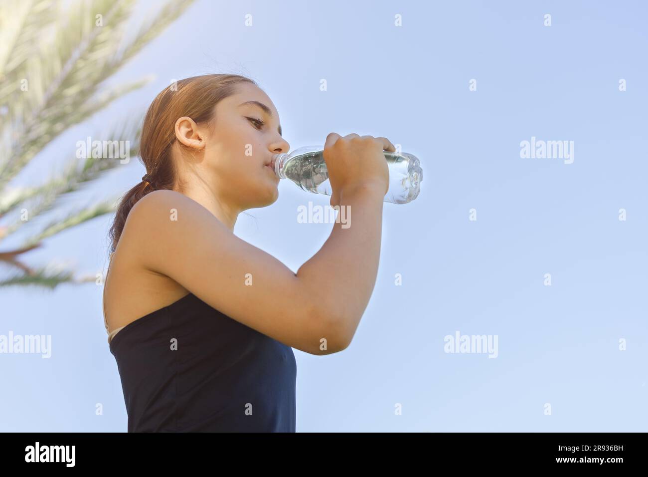 Low angle view of a young girl drinking water from a plastic bottle ...