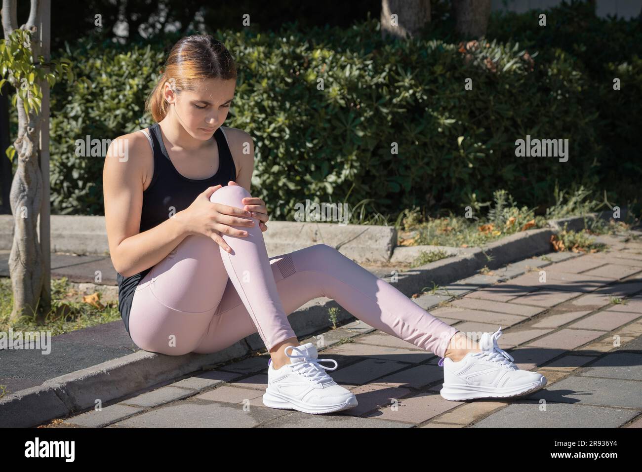 The girl holds an injured knee joint in her hands. Injury while running ...