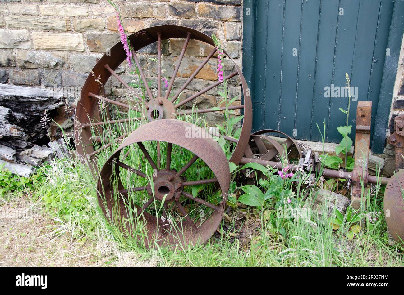 Rusted metal wheels next to stone wall. Abbeydale Industrial Hamlet ...