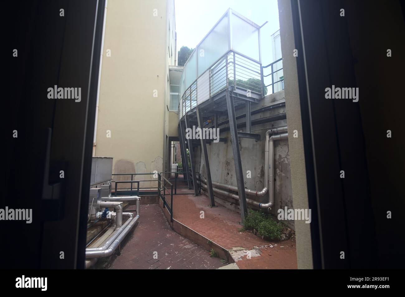 Back alley with machinery in a hospital seen from behind a window on a ...