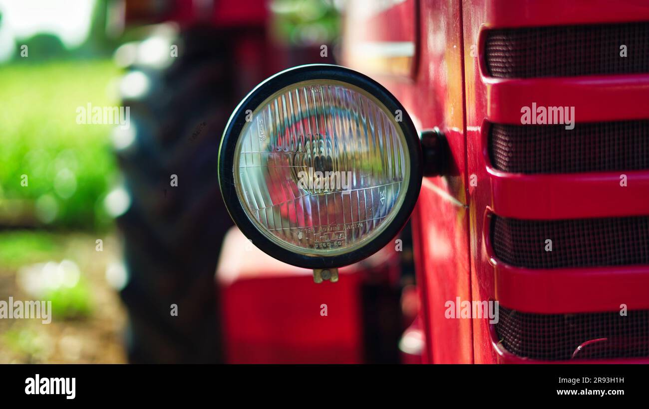 Headlight of a red tractor. Close up of the front of the tractor ...