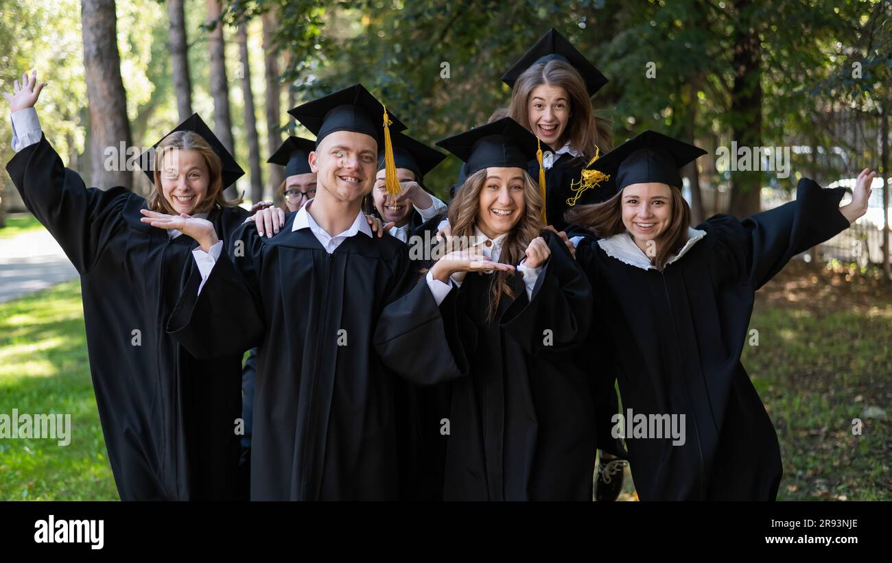 A group of graduates in robes congratulate each other on their ...
