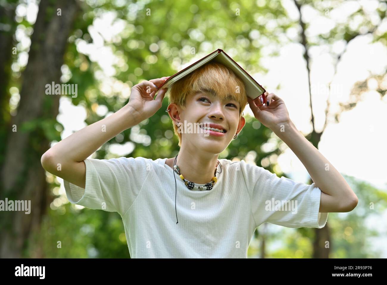 University student man putting open book on head, reading book in ...