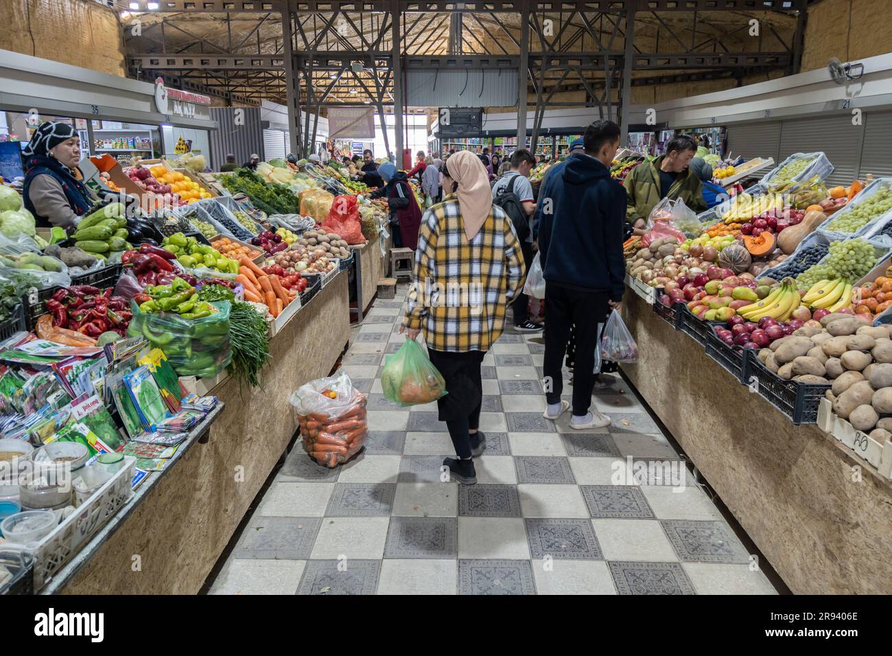 asian food market under roof with fresh vegetables and some clients ...