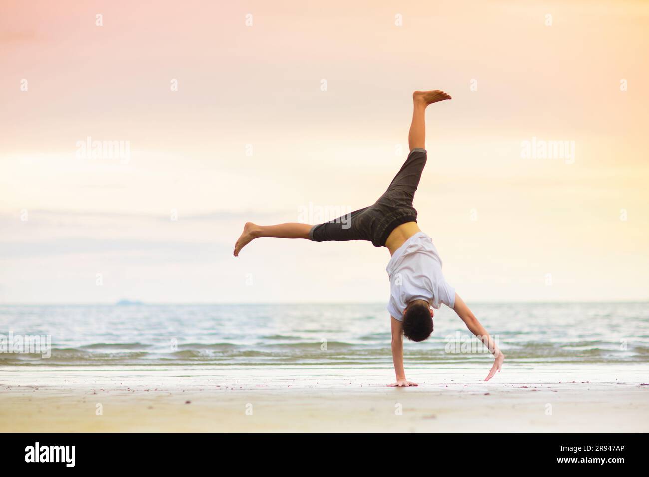 Teenager doing calisthenics exercise. Beach yoga at sunset. Teen boy ...
