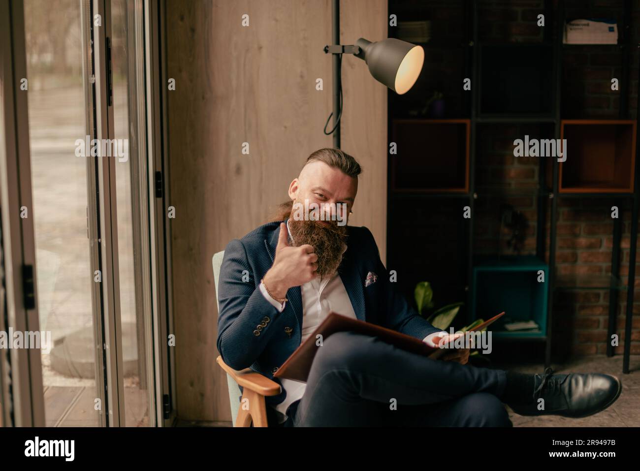 Handsome bearded man writing something on his notepad with his legs ...