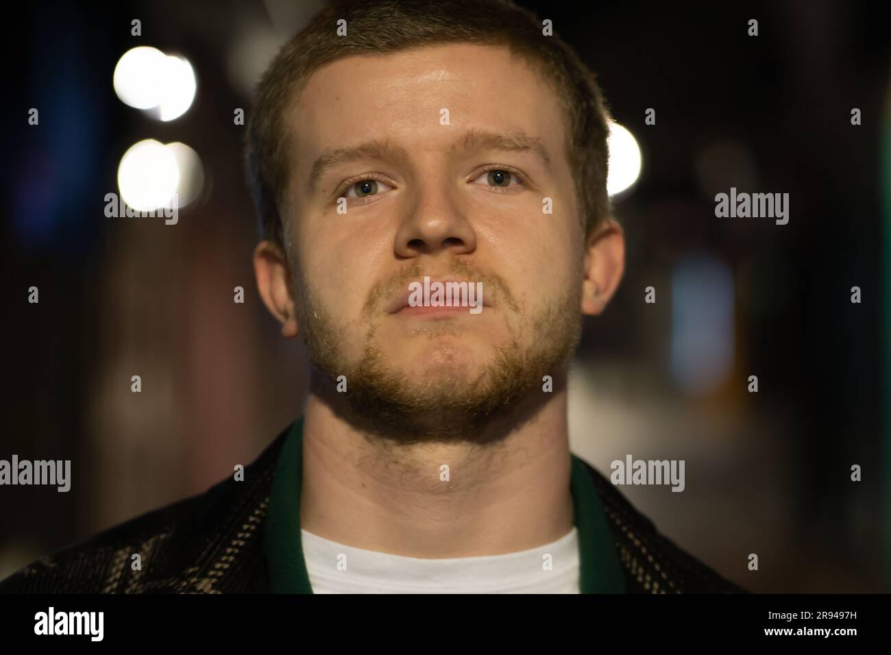 A close-up of a young, British man with green eyes looking into the ...