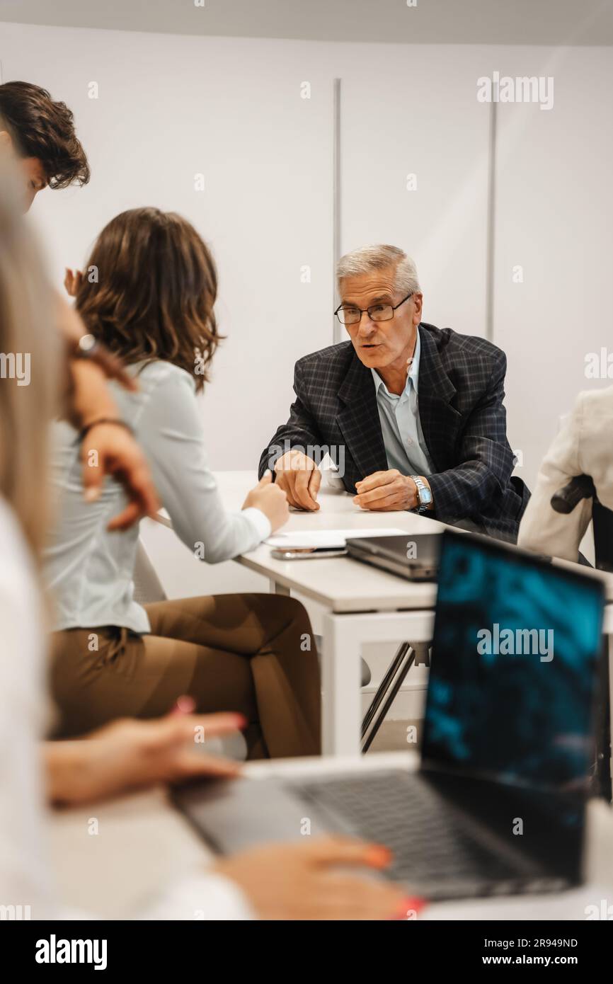 Older businessman giving tips and tricks to his young female colleague ...