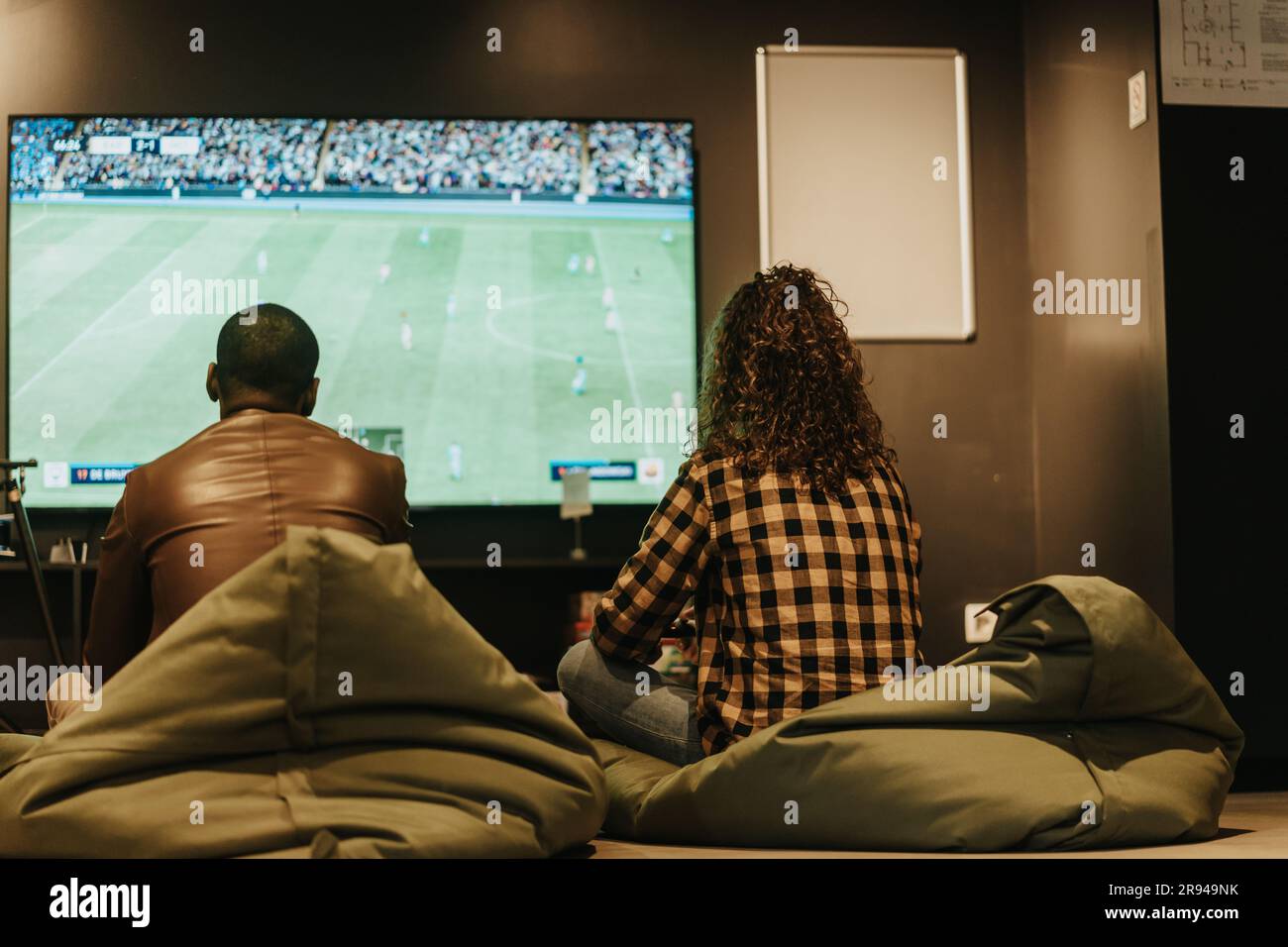 A back view shot of multiracial male colleagues playing games on a big ...