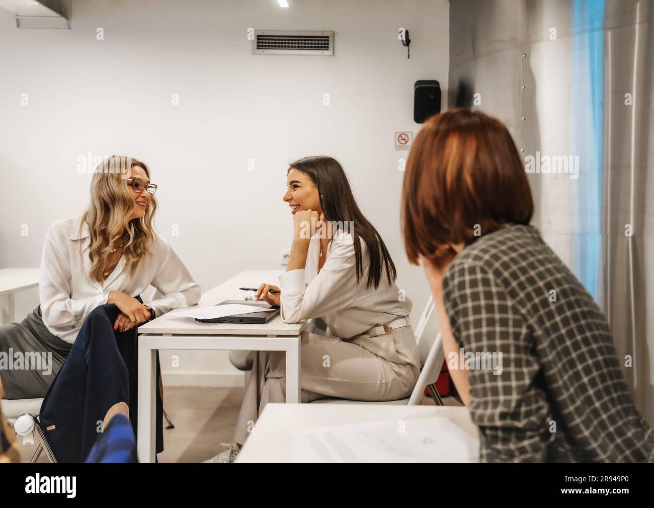 Female colleagues, young and middle-aged, having fun conversation and ...