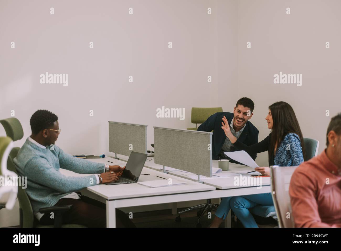 Three business colleagues laughing at the office while sitting at the office desk Stock Photo ...