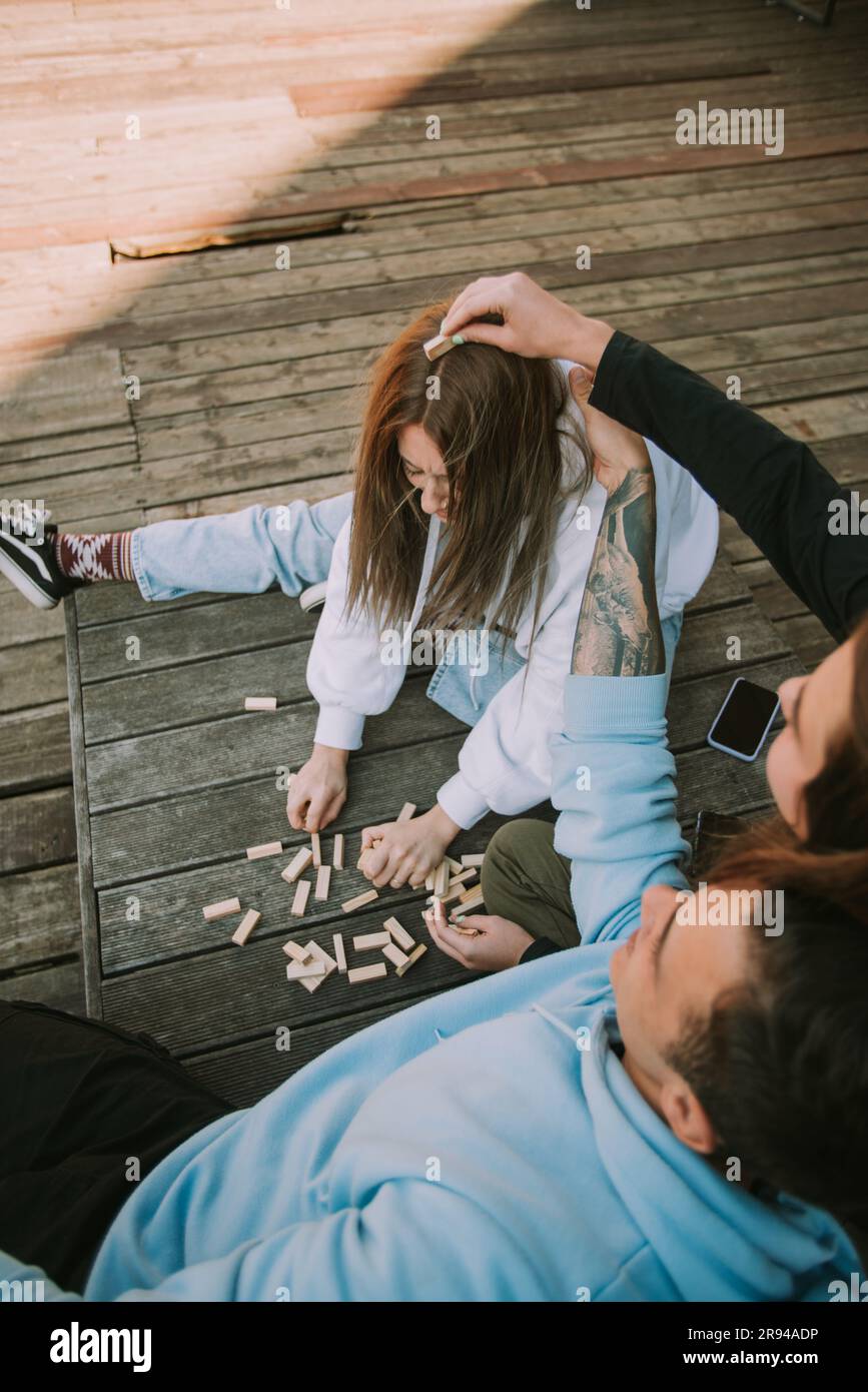 Blonde girl taking the scattered jenga while sitting with her friends ...