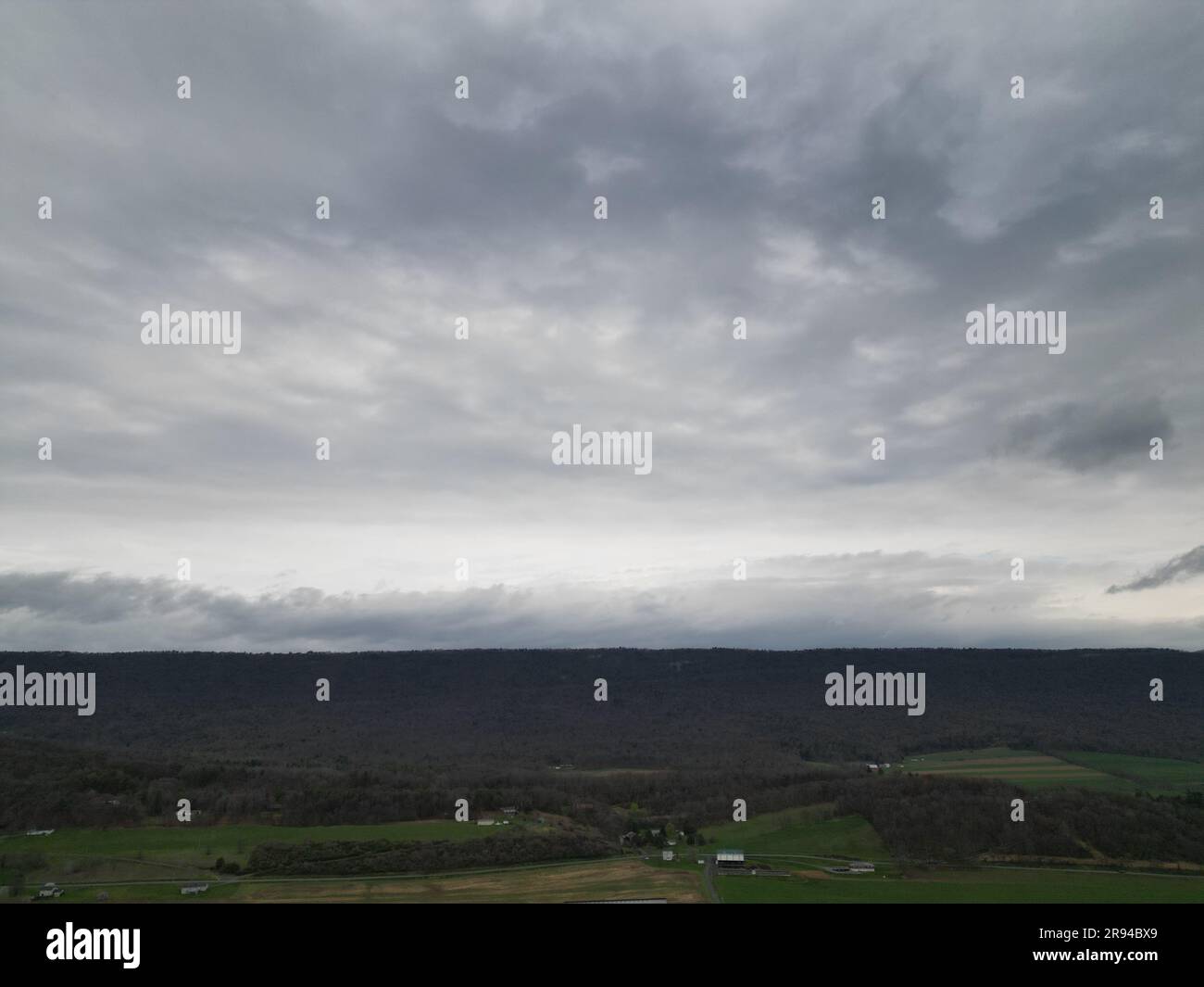 An aerial view of a scenic landscape featuring a cloudy sky and a small ...