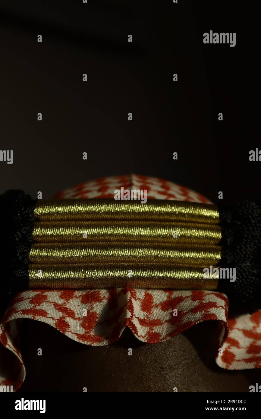 An intricately patterned Saudi Keffiyeh with a golden band is displayed ...