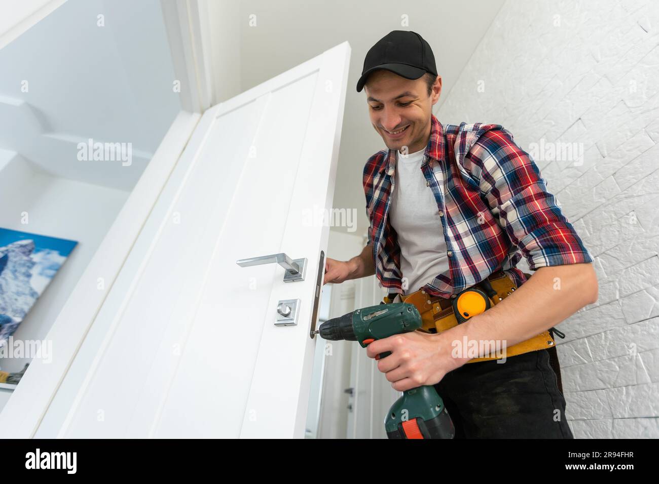 Carpenter repairing door lock. Installing a door handle Stock Photo - Alamy