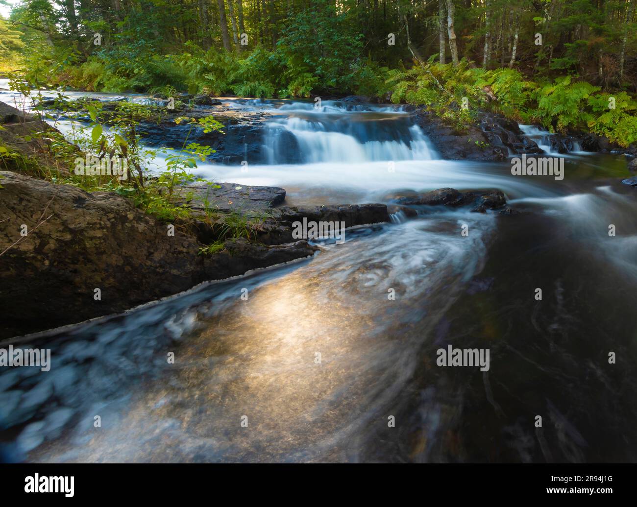 Sun glowing on a pool of water below a Maine waterfall Stock Photo - Alamy