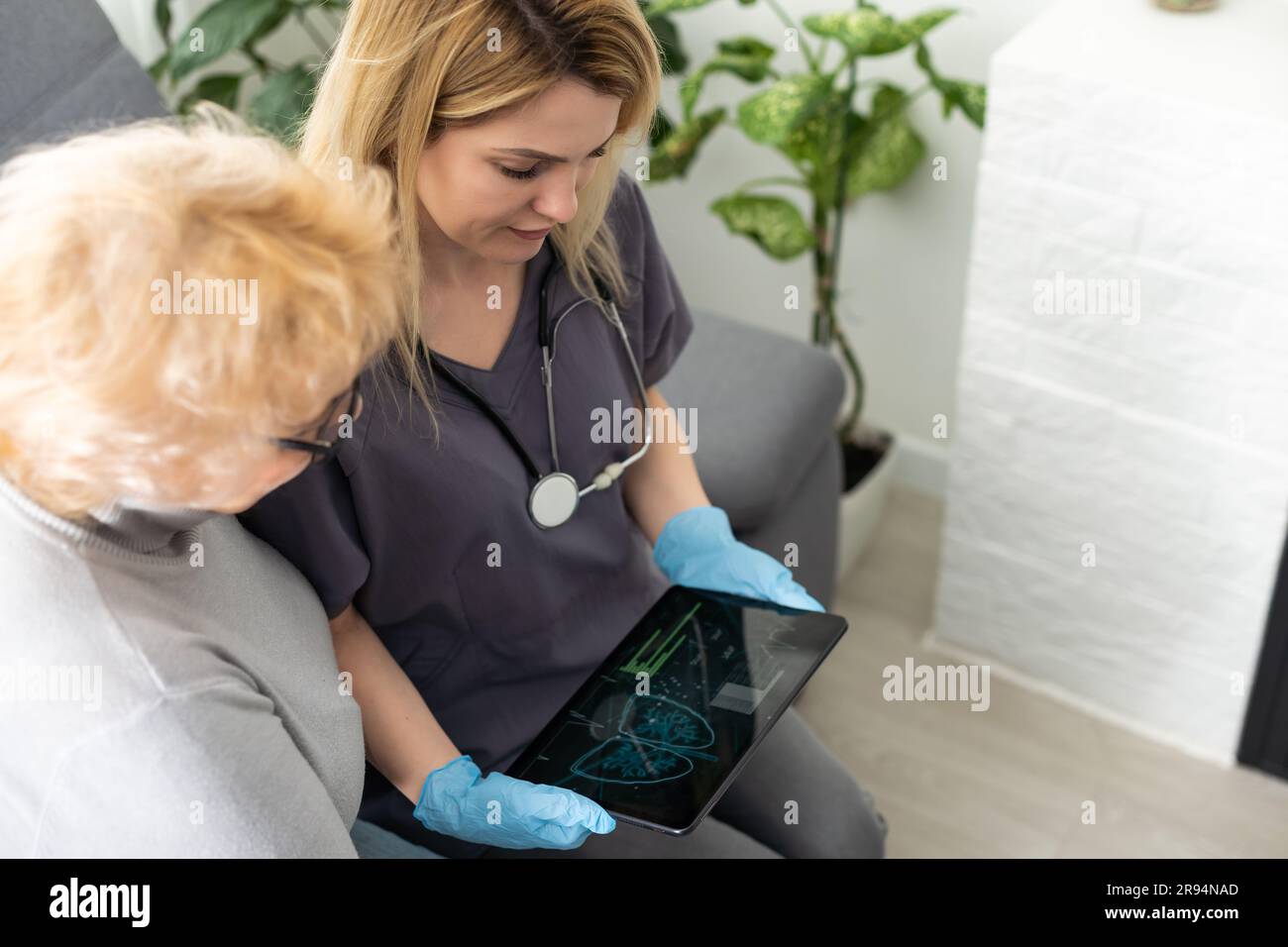 Serious GP doctor showing tablet screen to old 70s female patient ...