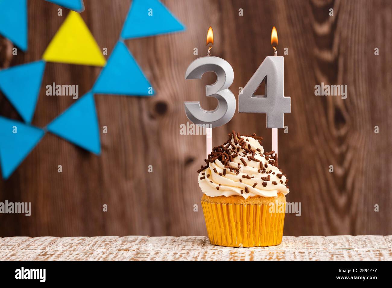burning candle - birthday number 34 on wooden background with pennants ...