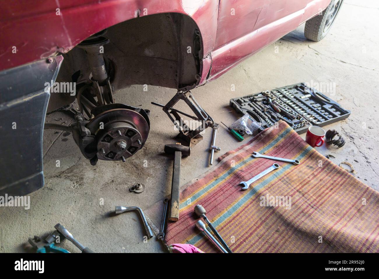 process of repair an old red car with old poor tools on concrete ...